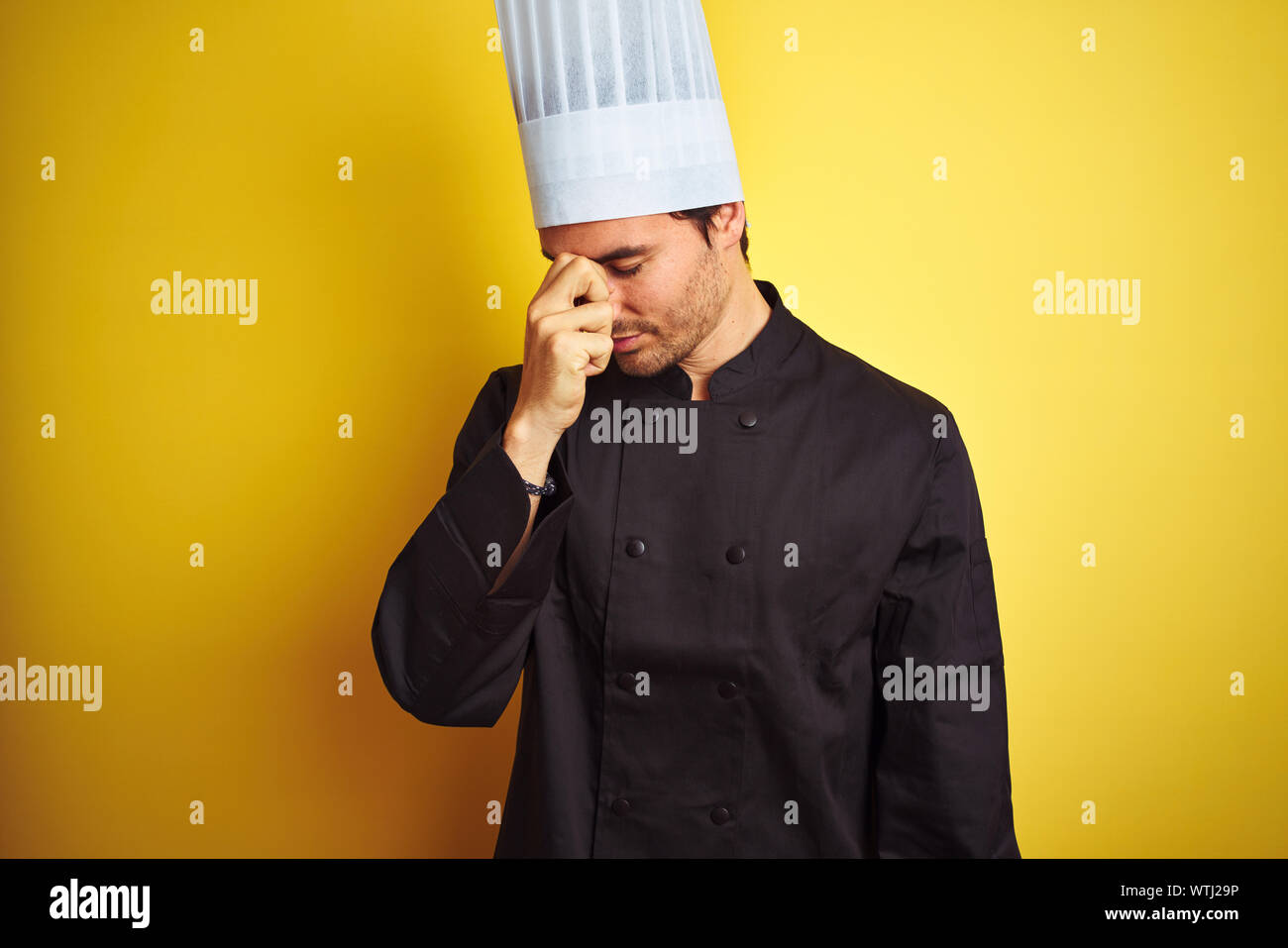 Young chef man wearing uniform and hat standing over isolated yellow ...