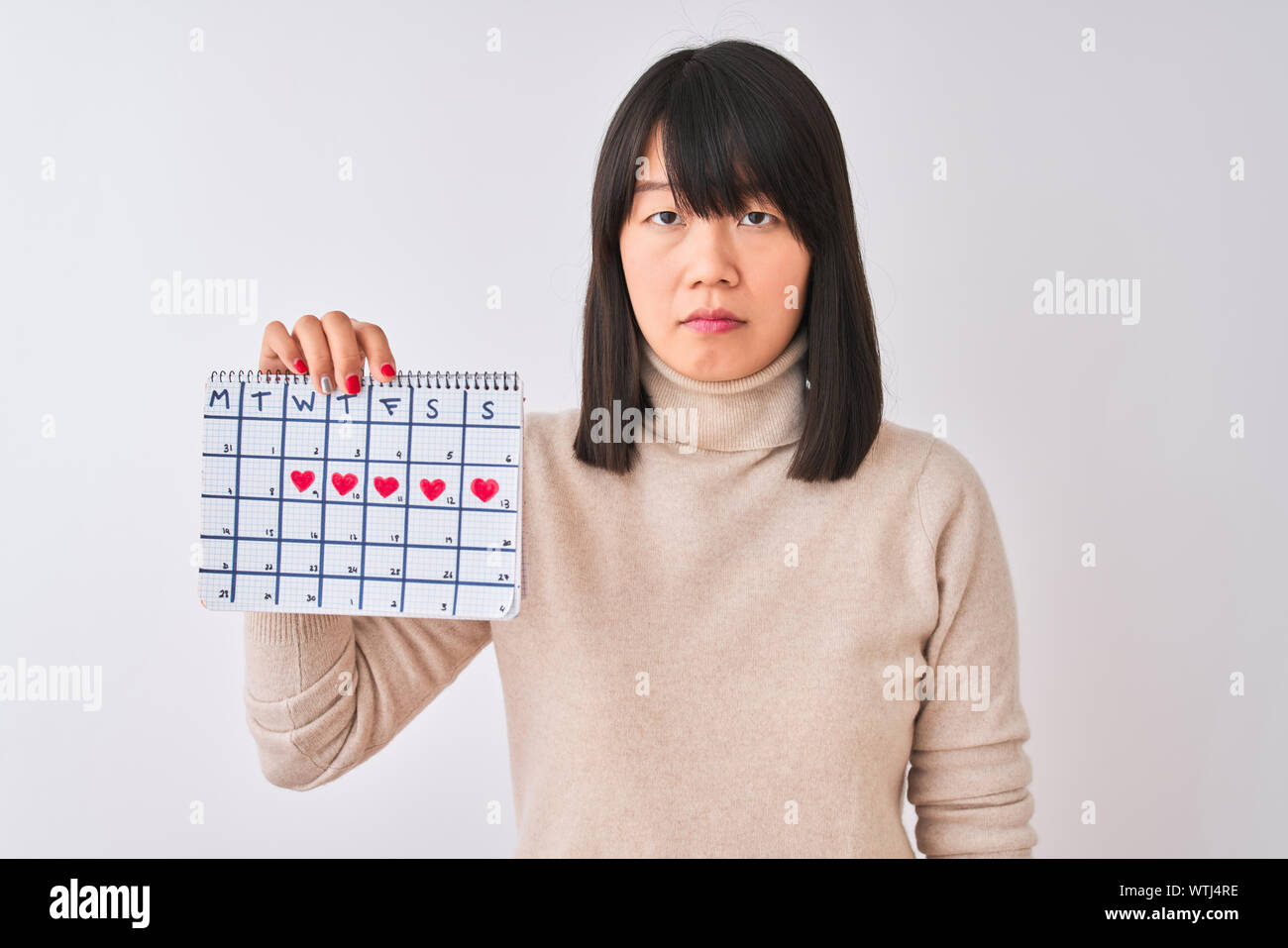 Young beautiful Chinese woman holding menstruation calendar over ...