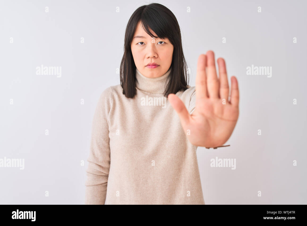 Young beautiful chinese woman wearing turtleneck sweater over isolated ...