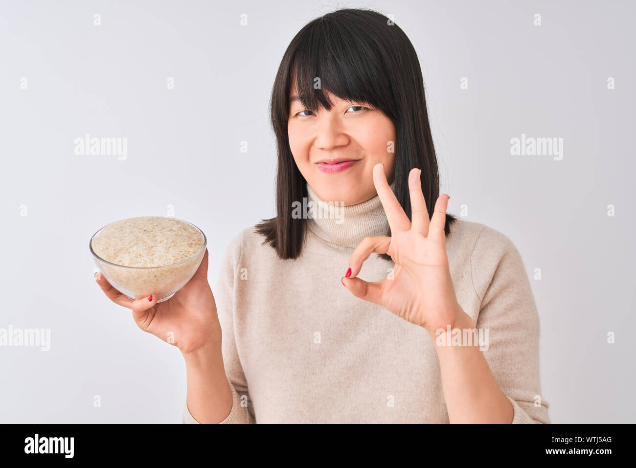 Young beautiful Chinese woman holding bowl with rice over isolated ...