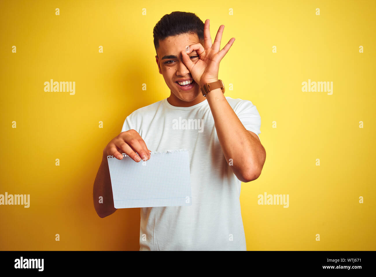 Young brazilian man showing paper banner standing over isolated yellow ...