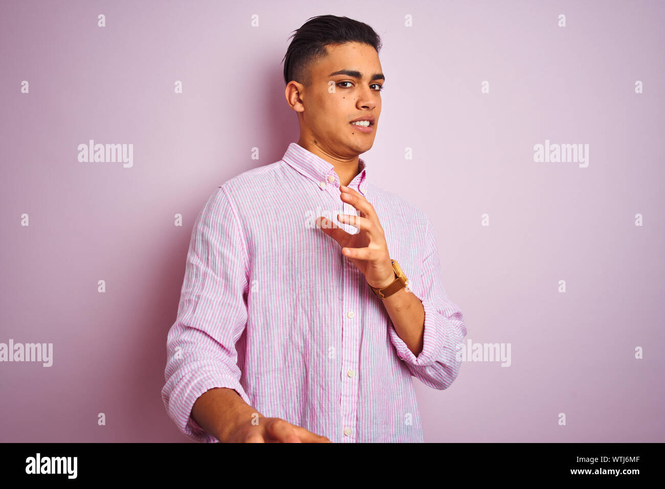 Young brazilian man wearing shirt standing over isolated pink ...