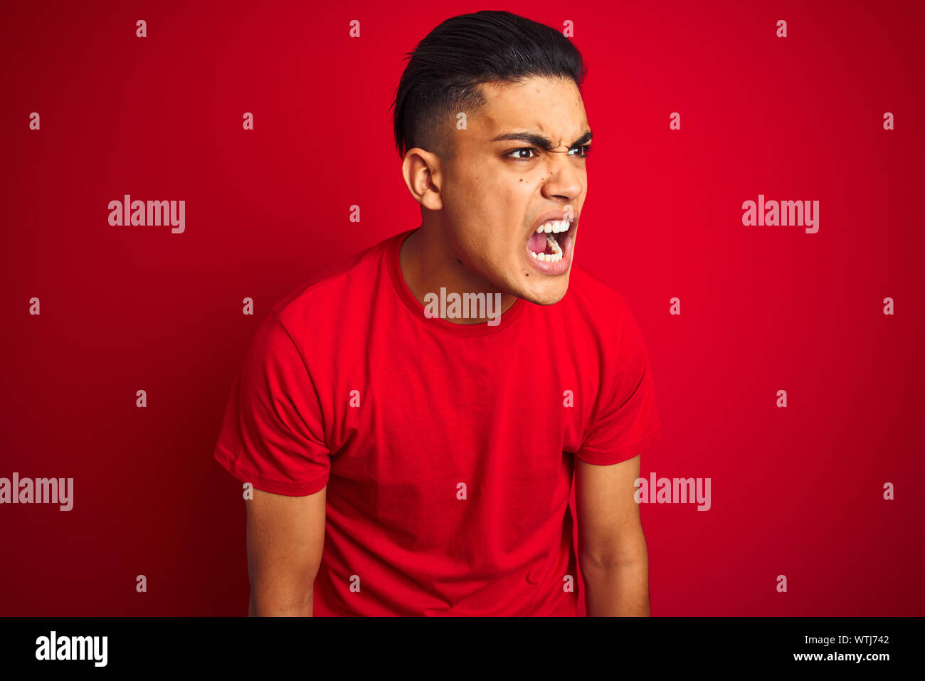 Young brazilian man wearing t-shirt standing over isolated red ...