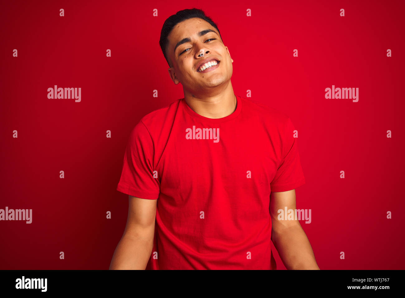 Young brazilian man wearing t-shirt standing over isolated red ...