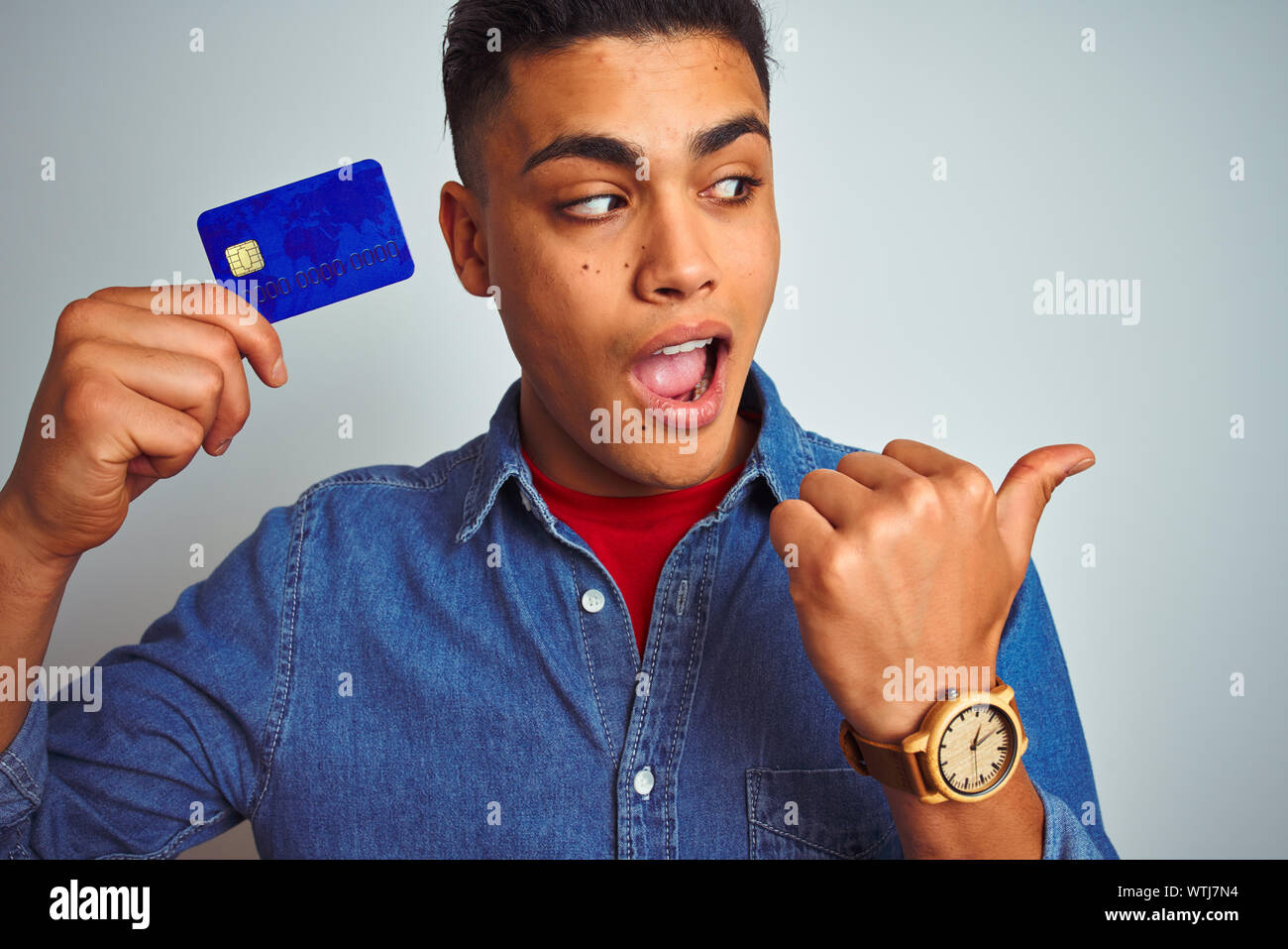Young brazilian customer man holding credit card standing over isolated ...