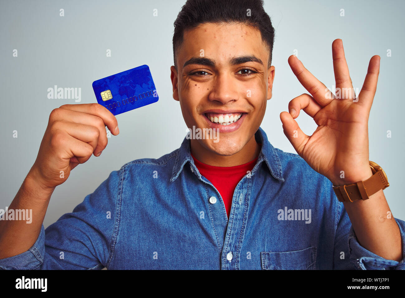 Young brazilian customer man holding credit card standing over isolated ...