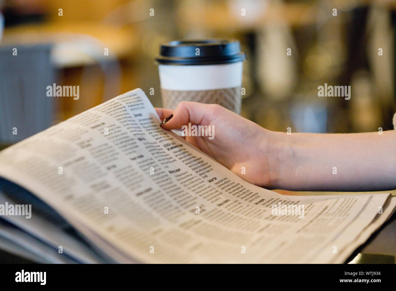 Female hand holding newspaper Stock Photo - Alamy