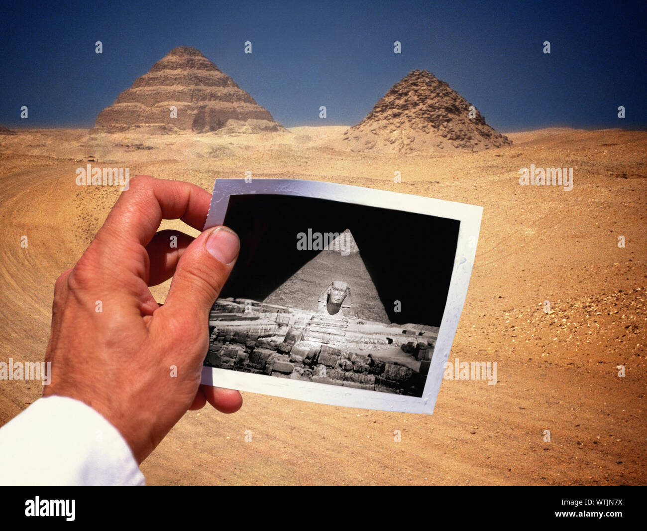 A man is comparing a photograph of a pyramid with the real one, Egypt ...