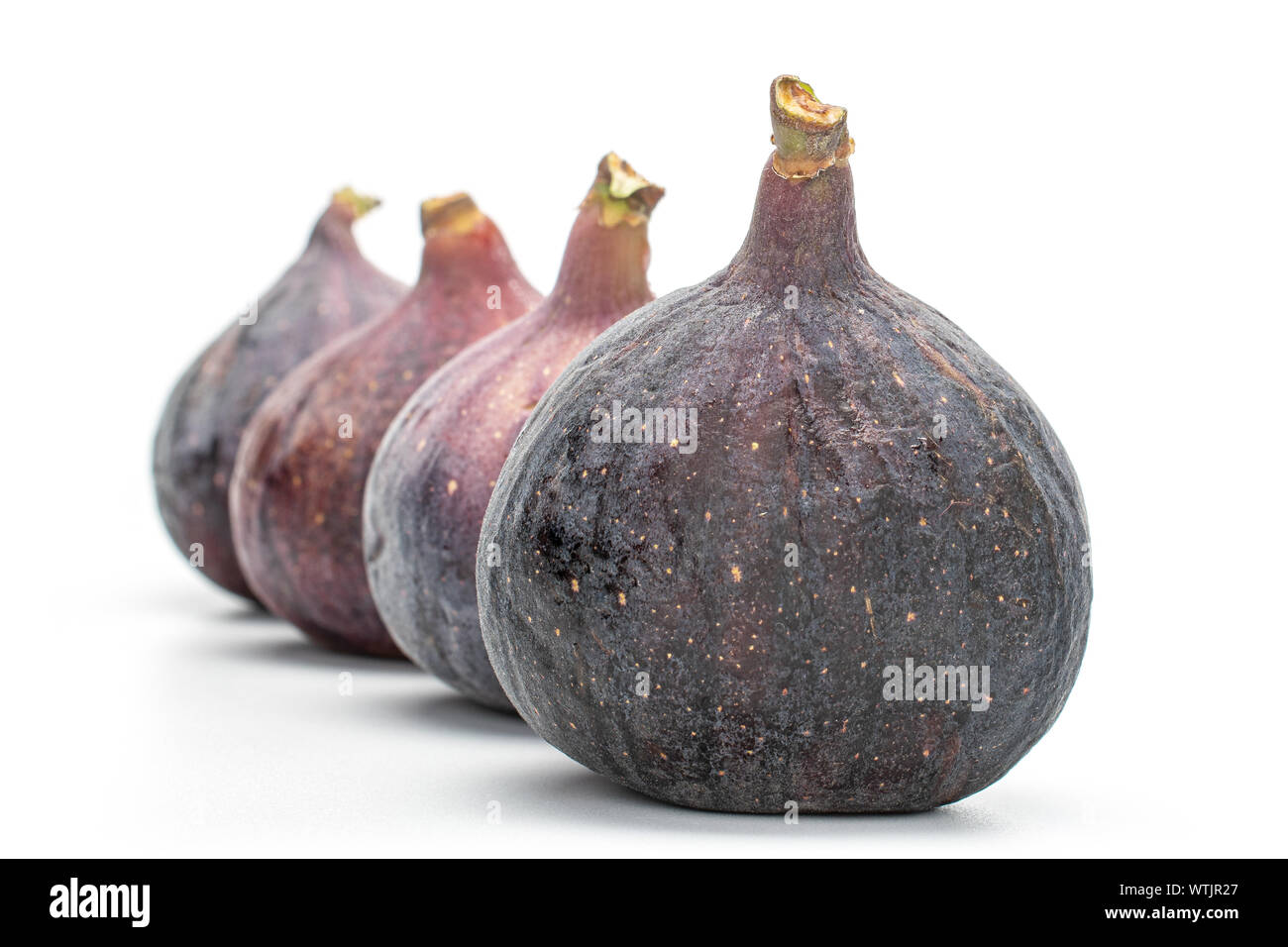 Group of four whole fresh fig fruit in row isolated on white background ...