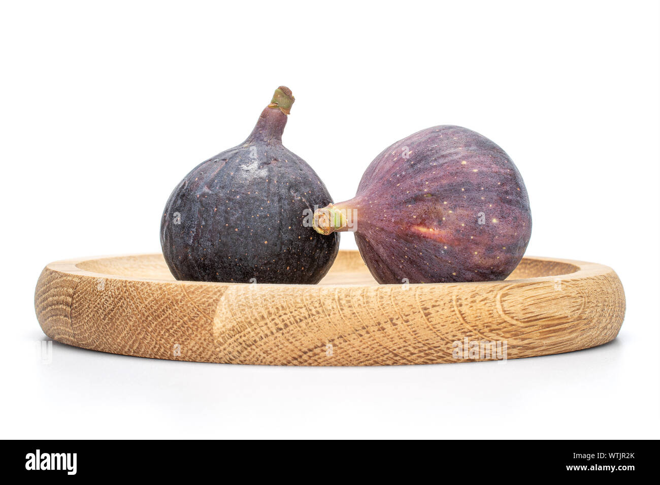 Group of two whole fresh fig fruit on bamboo plate isolated on white ...