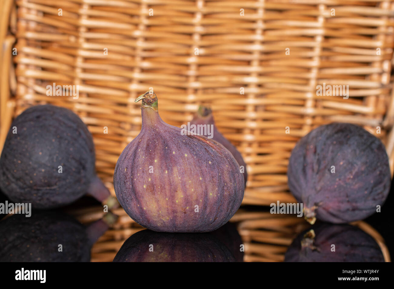 Group of four whole fresh fig fruit with braided rattan behind Stock ...