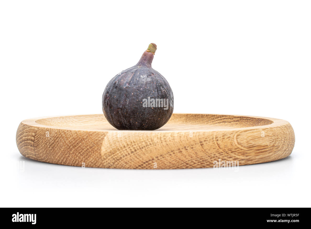 One whole fresh fig fruit on bamboo plate isolated on white background ...