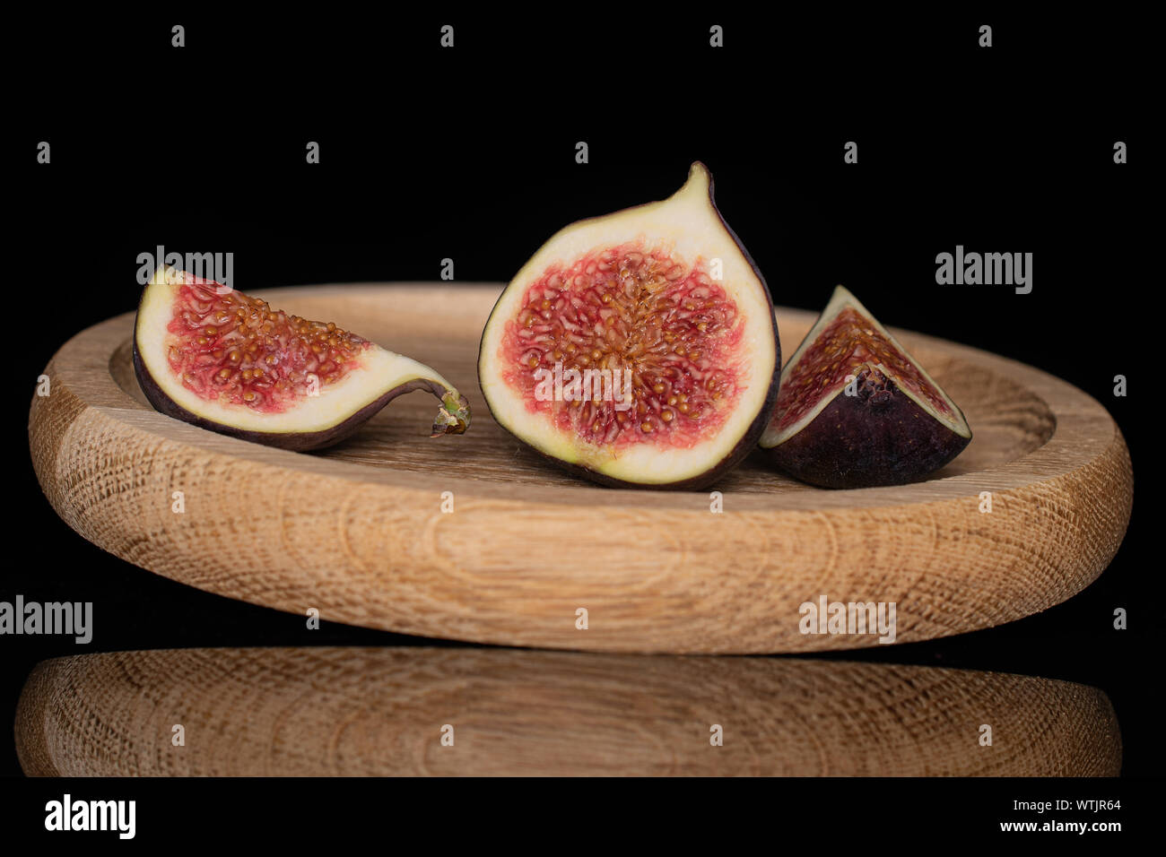 Group of one half two slices of fresh fig fruit on bamboo plate ...