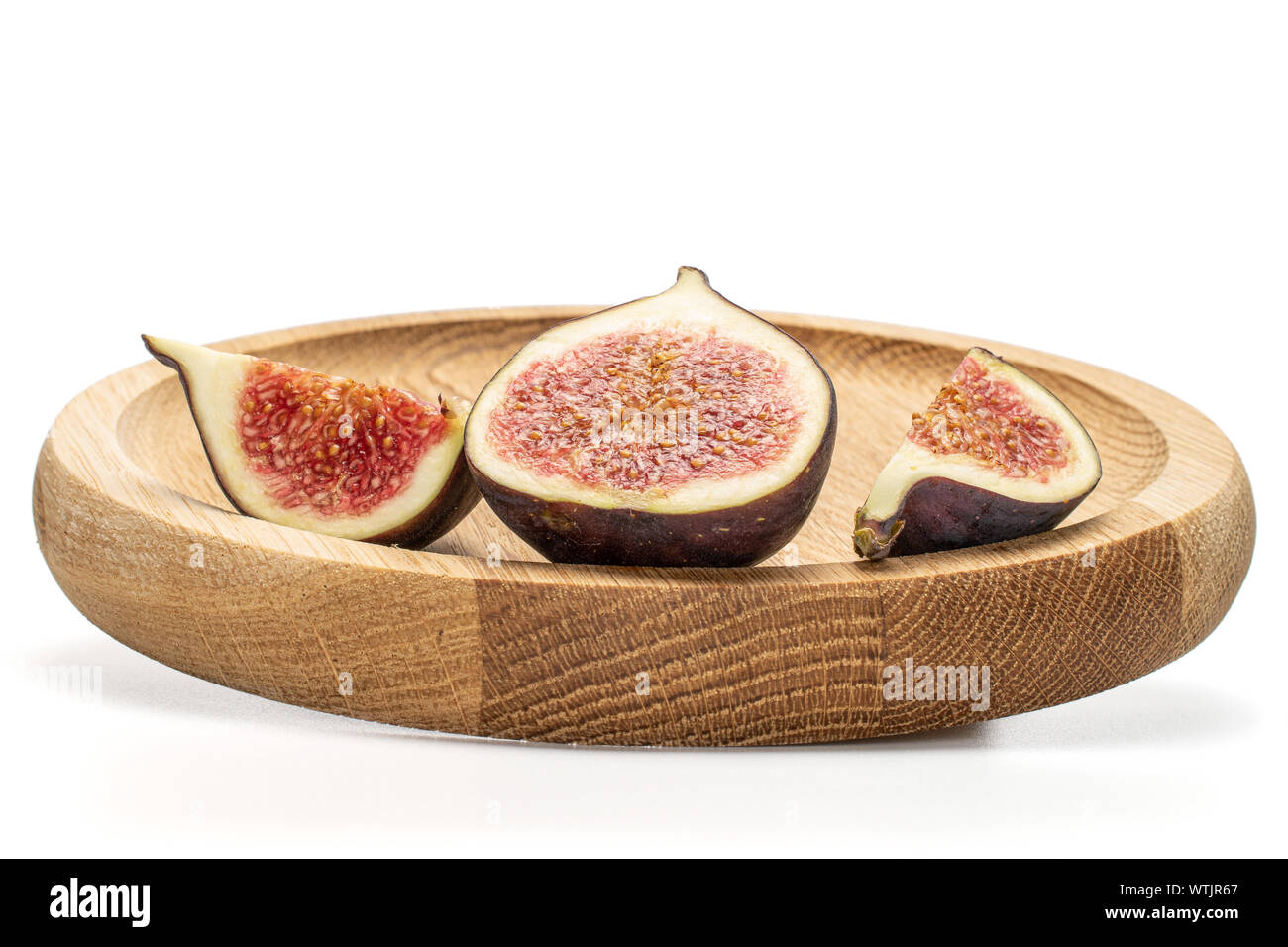 Group of one half two slices of fresh fig fruit on bamboo plate ...