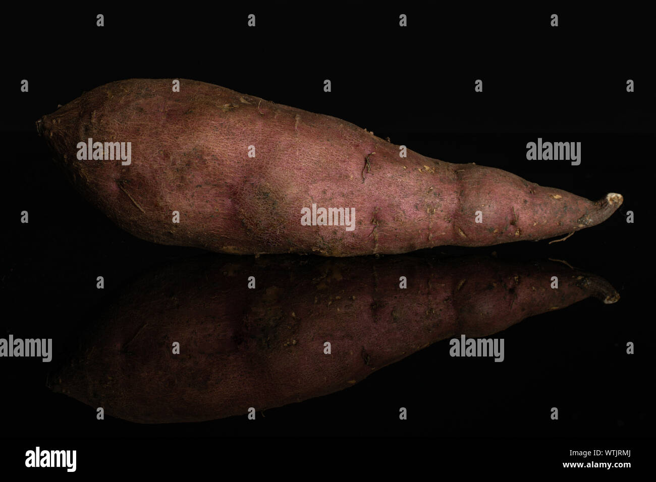 One whole fresh brown sweet potato isolated on black glass Stock Photo ...