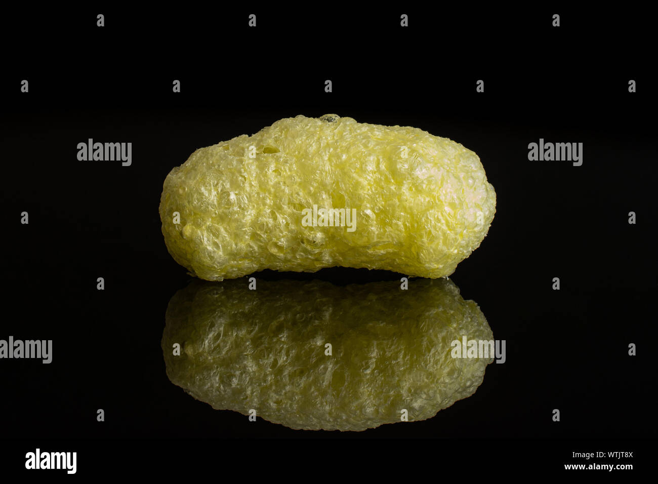One whole salted yellow corn puff isolated on black glass Stock Photo ...