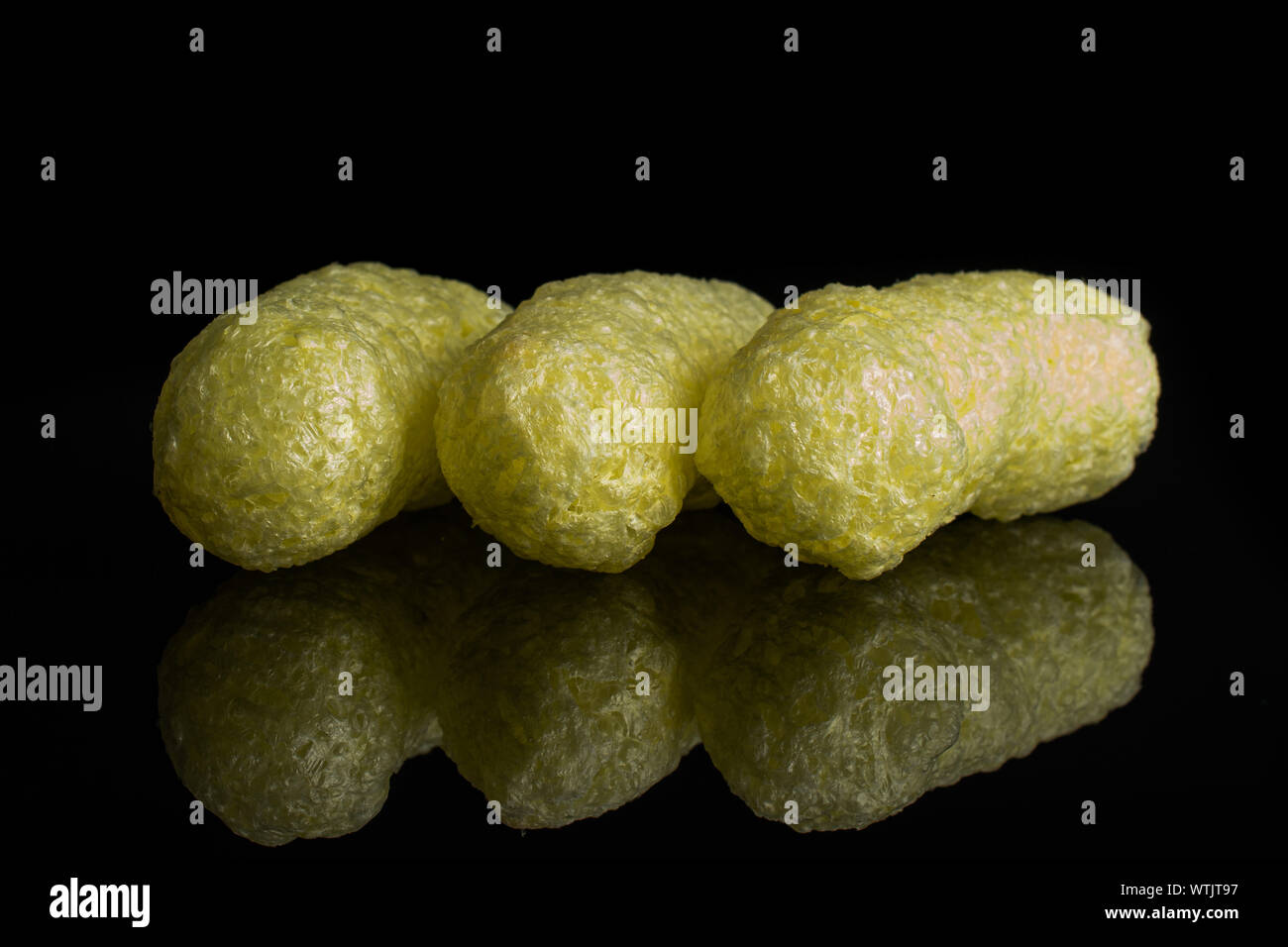 Group of three whole salted yellow corn puff isolated on black glass ...