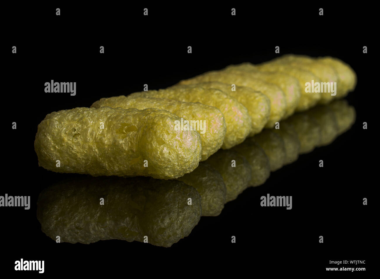 Lot of whole salted yellow corn puff isolated on black glass Stock ...