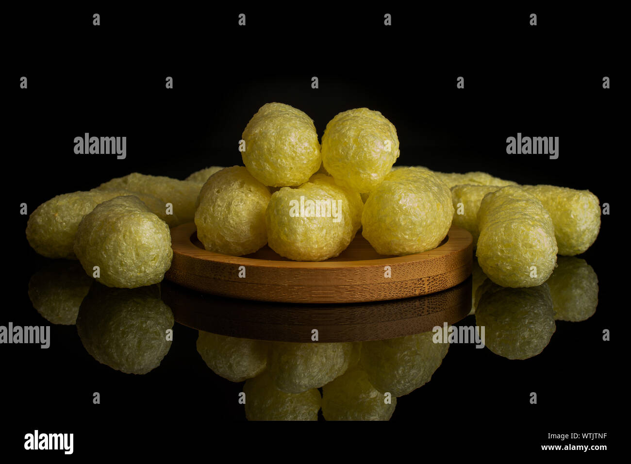 Lot of whole salted yellow corn puff on bamboo coaster isolated on ...