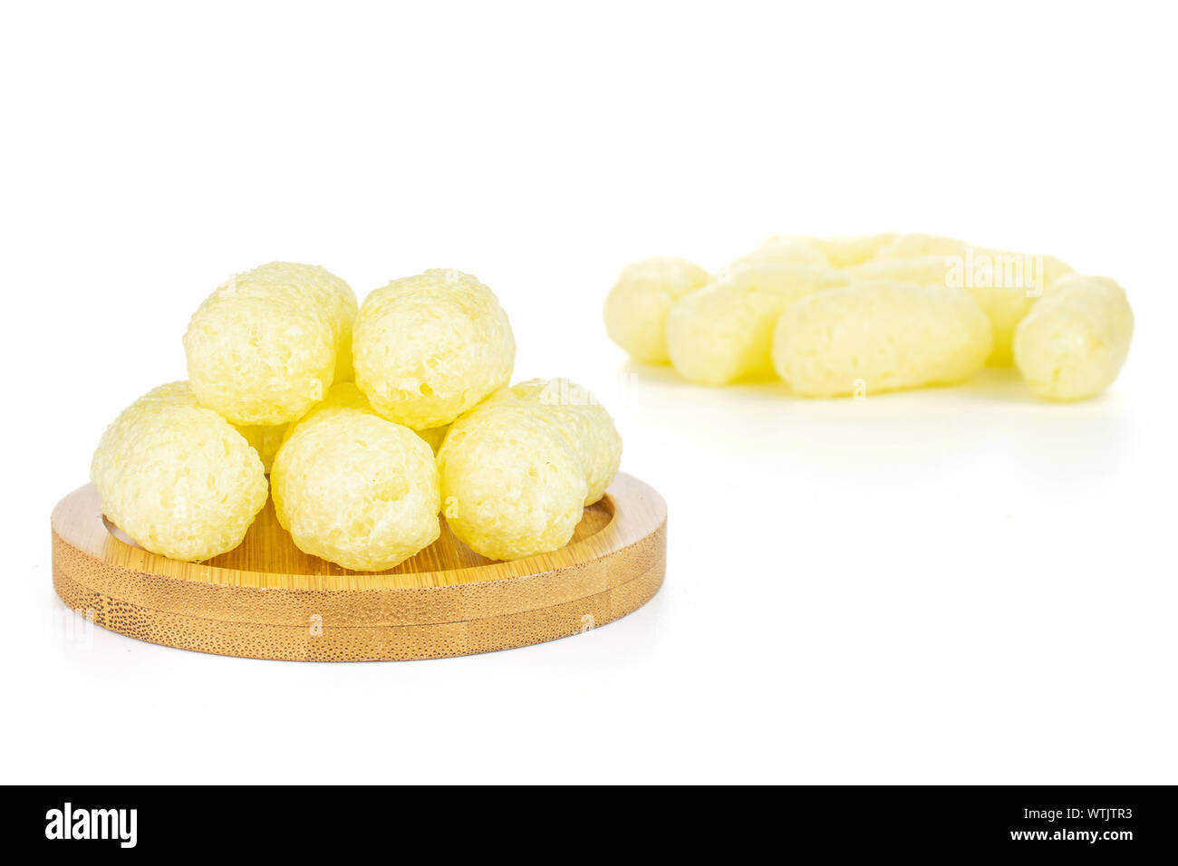Lot of whole salted yellow corn puff on bamboo coaster isolated on ...