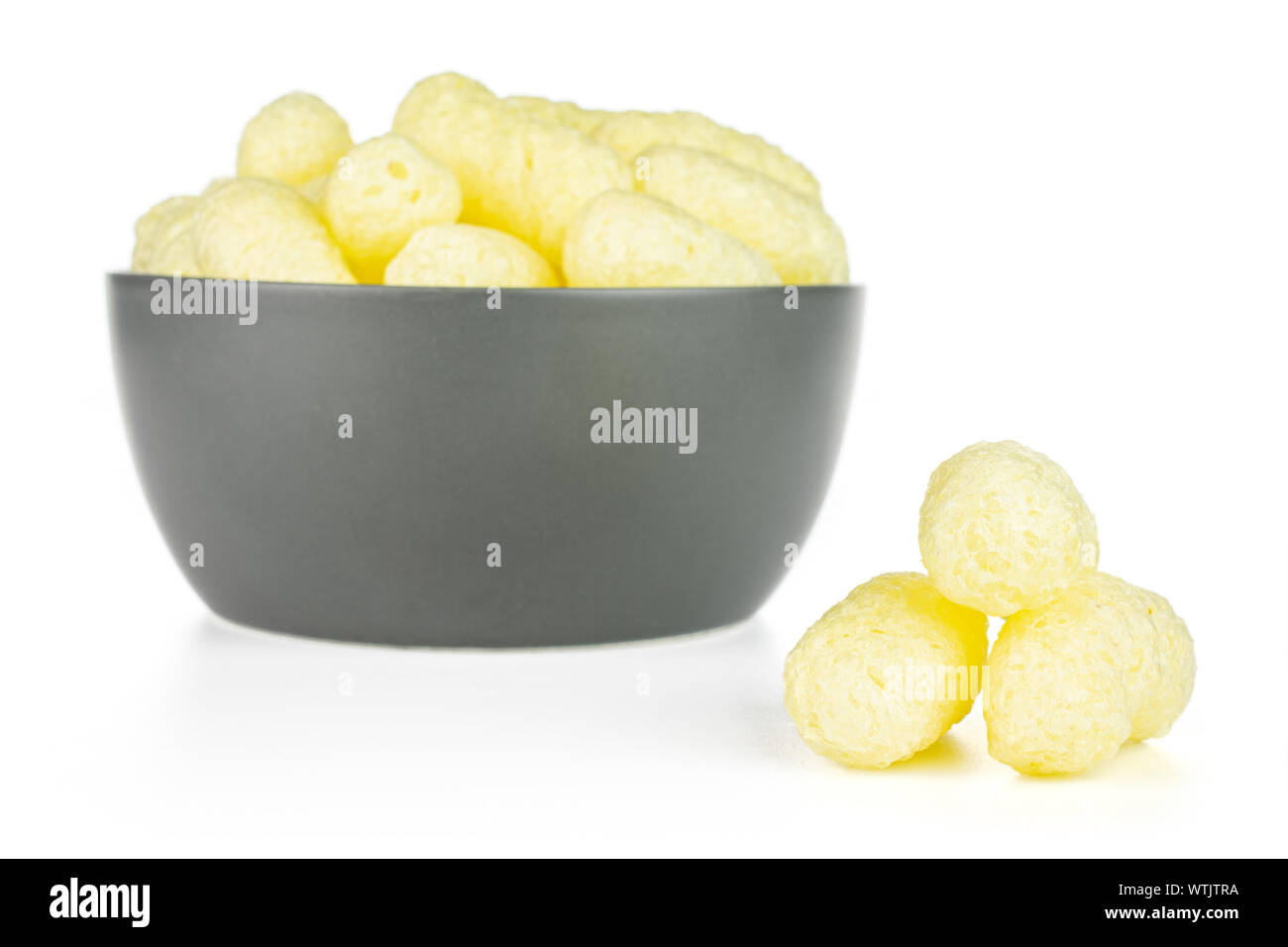 Lot of whole salted yellow corn puff in gray ceramic bowl isolated on ...