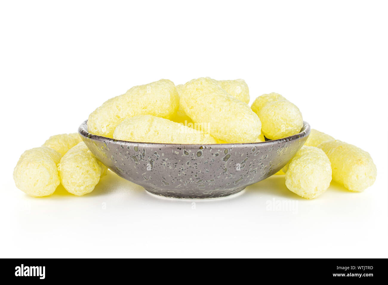 Lot of whole salted yellow corn puff in dark ceramic bowl isolated on ...