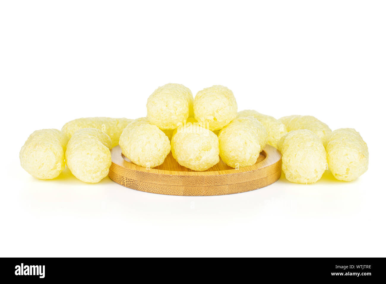 Lot of whole salted yellow corn puff on bamboo coaster isolated on ...