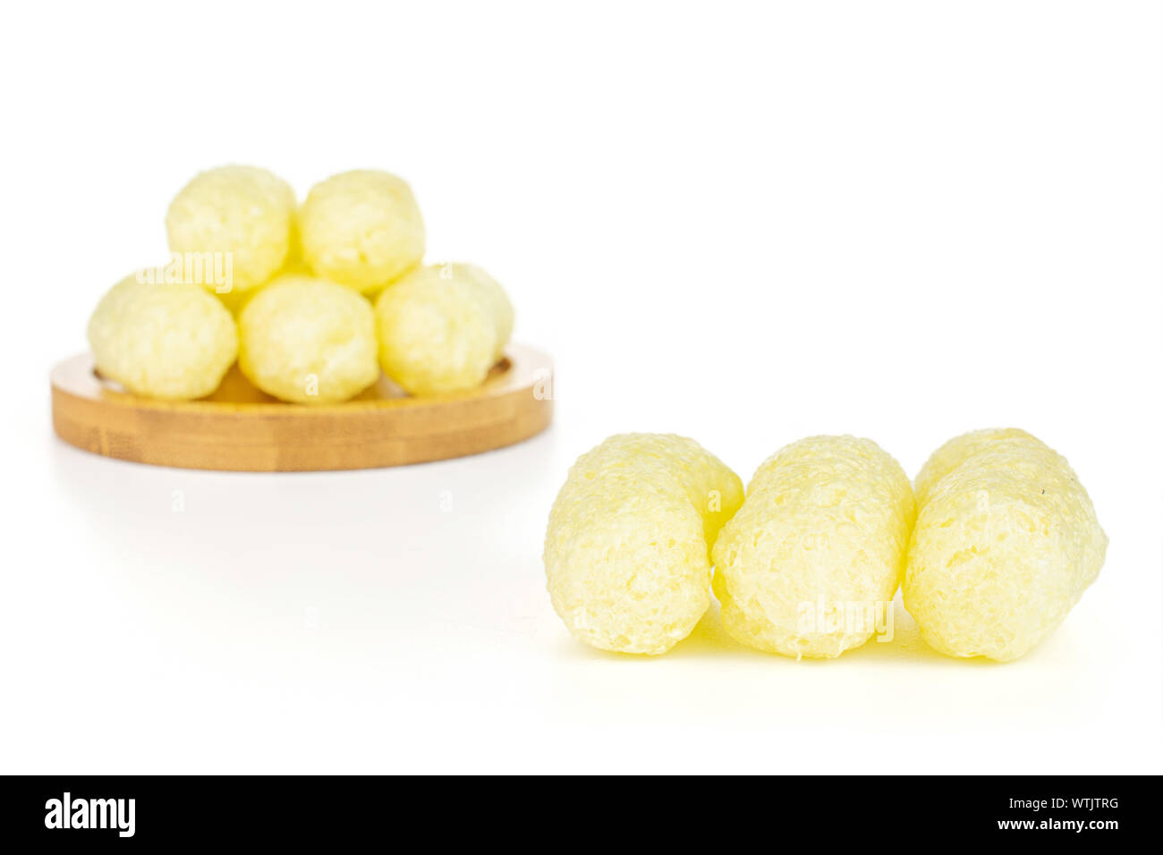 Group of eight whole salted yellow corn puff on bamboo coaster isolated ...
