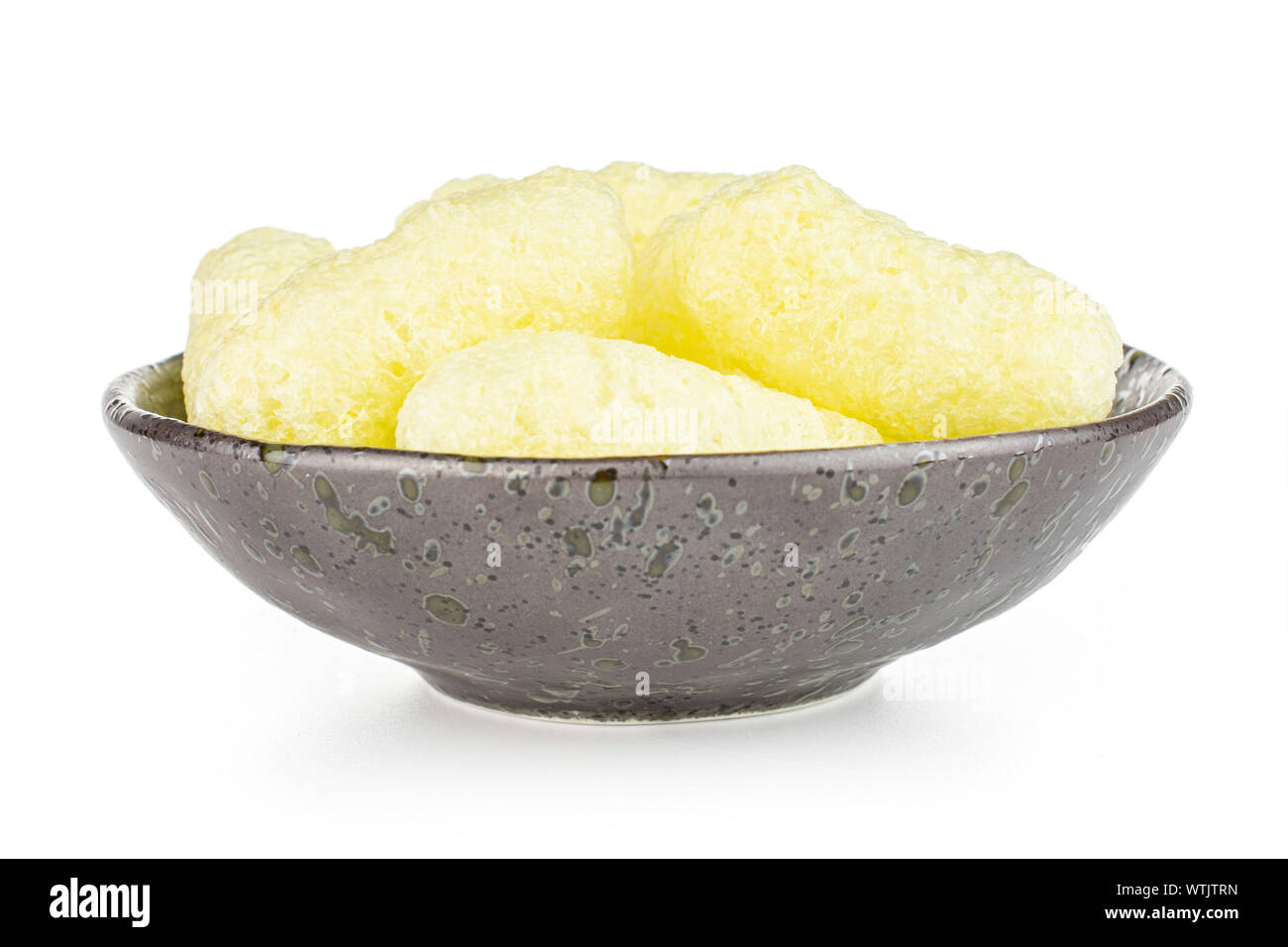 Lot of whole salted yellow corn puff in dark ceramic bowl isolated on ...