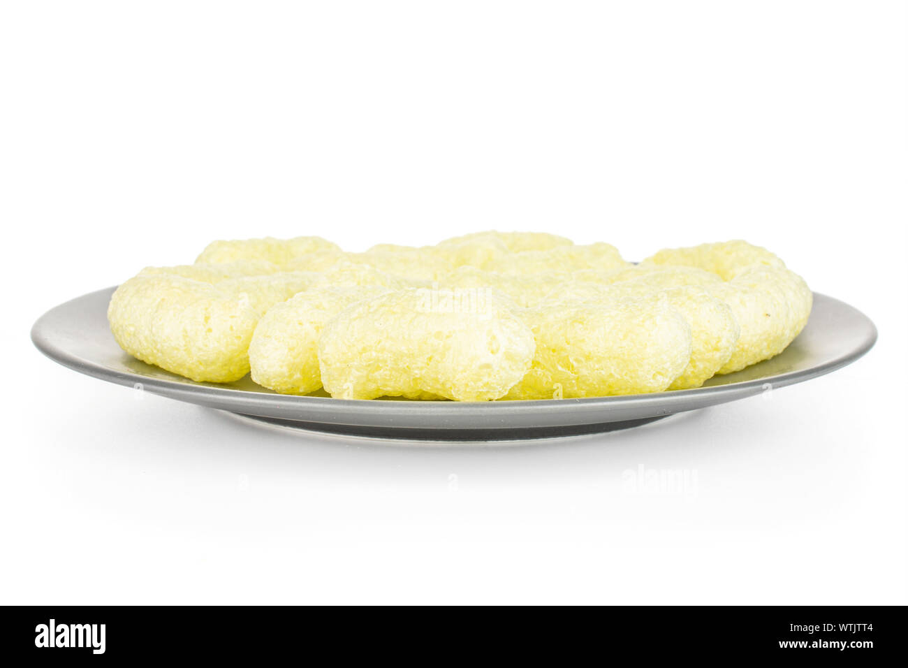 Lot of whole salted yellow corn puff on gray ceramic plate isolated on ...