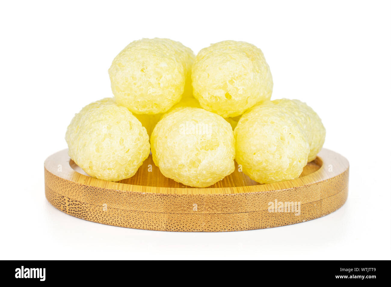 Group of five whole salted yellow corn puff on bamboo coaster isolated ...
