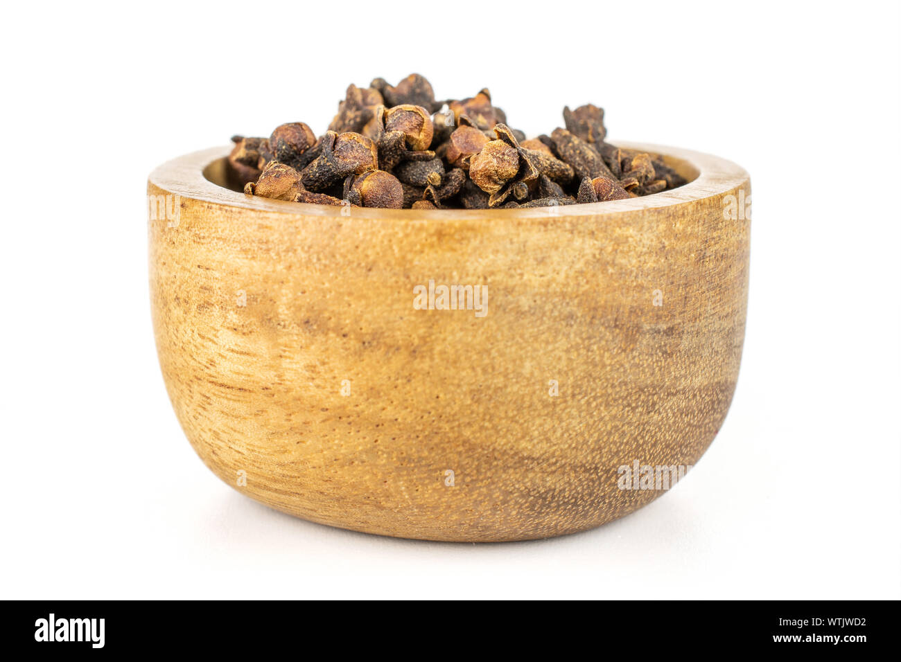 Lot of whole dry brown clove in tiny wooden bowl isolated on white ...