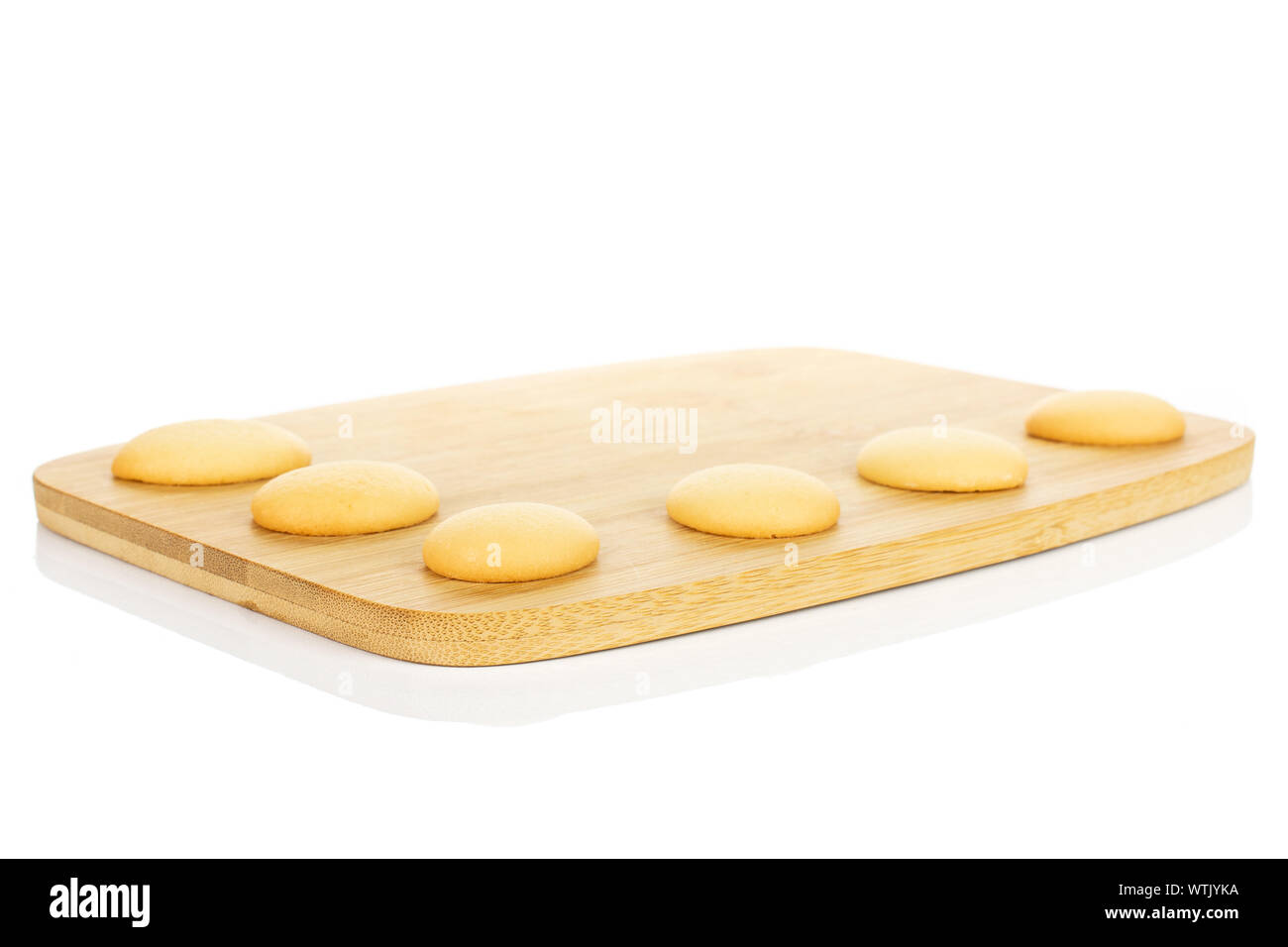 Group of six whole sweet golden sponge biscuit on bamboo cutting board ...