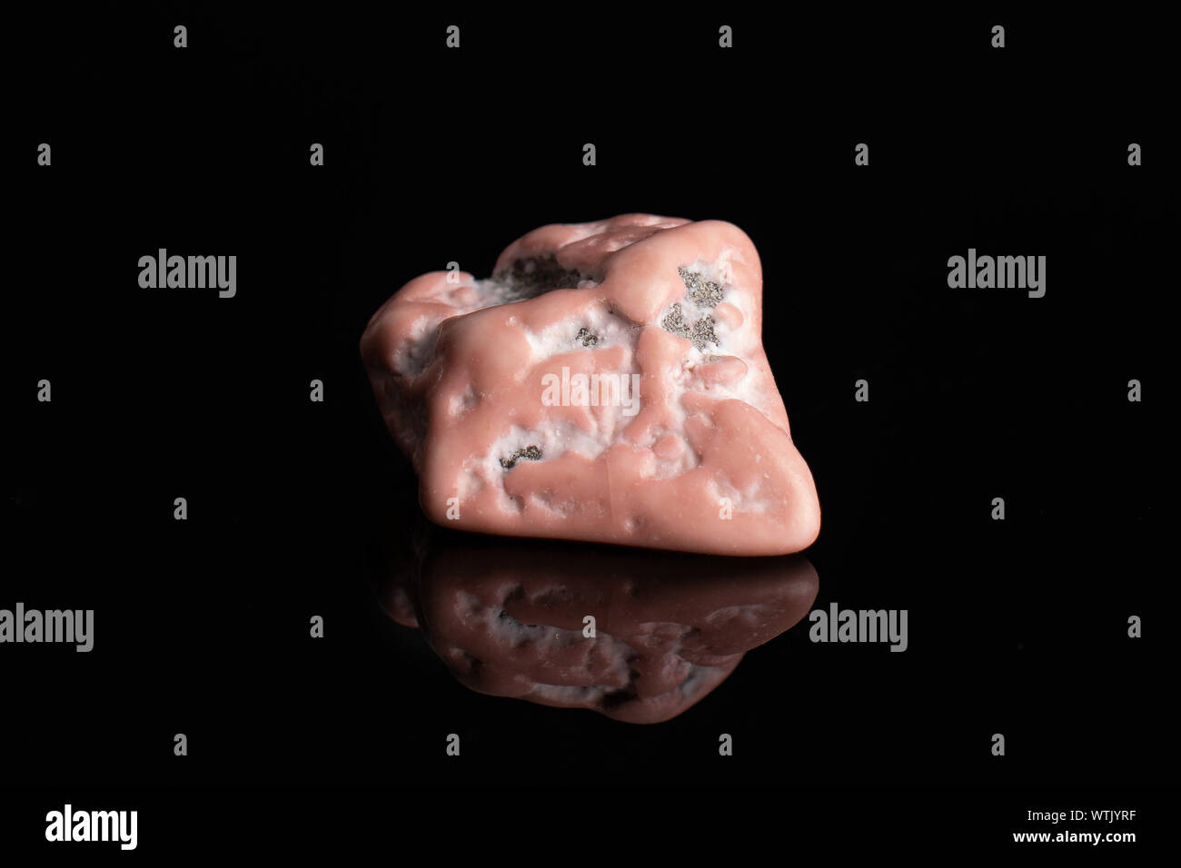 One whole pink sweet chocolate stone isolated on black glass Stock ...