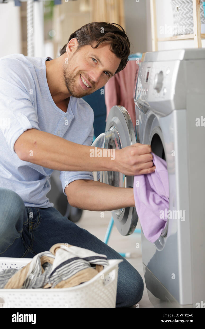 man putting clothes in washing machine Stock Photo - Alamy