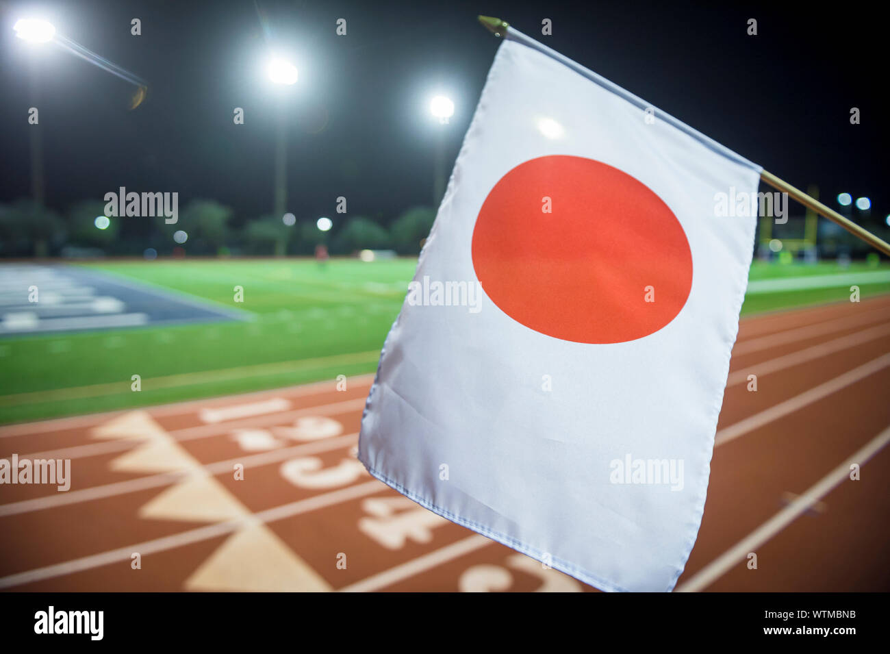Japanese flag hanging in front of running floodlit track at night Stock ...