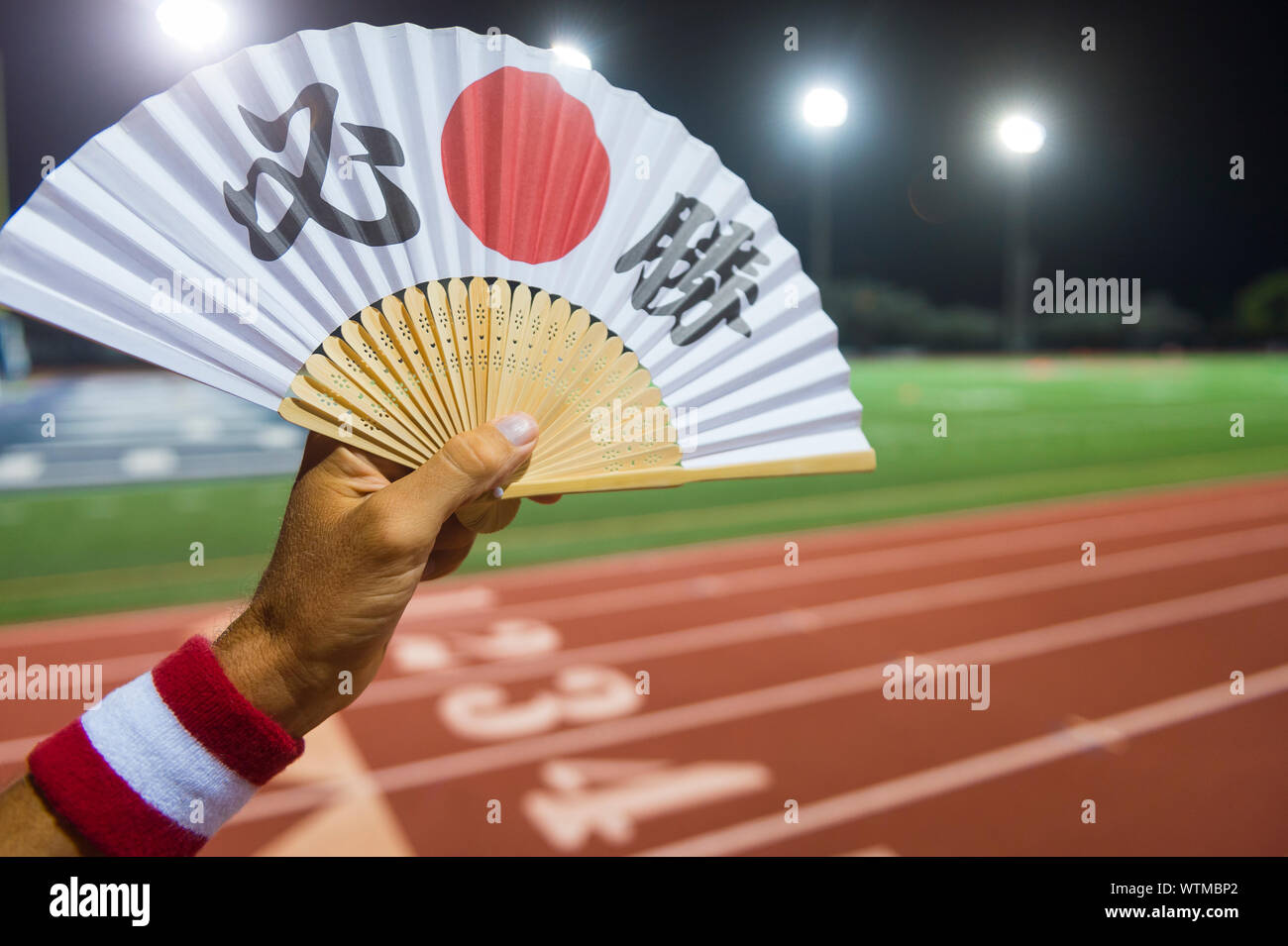 Hand of Japanese sports athlete standing outdoors holding a fan ...