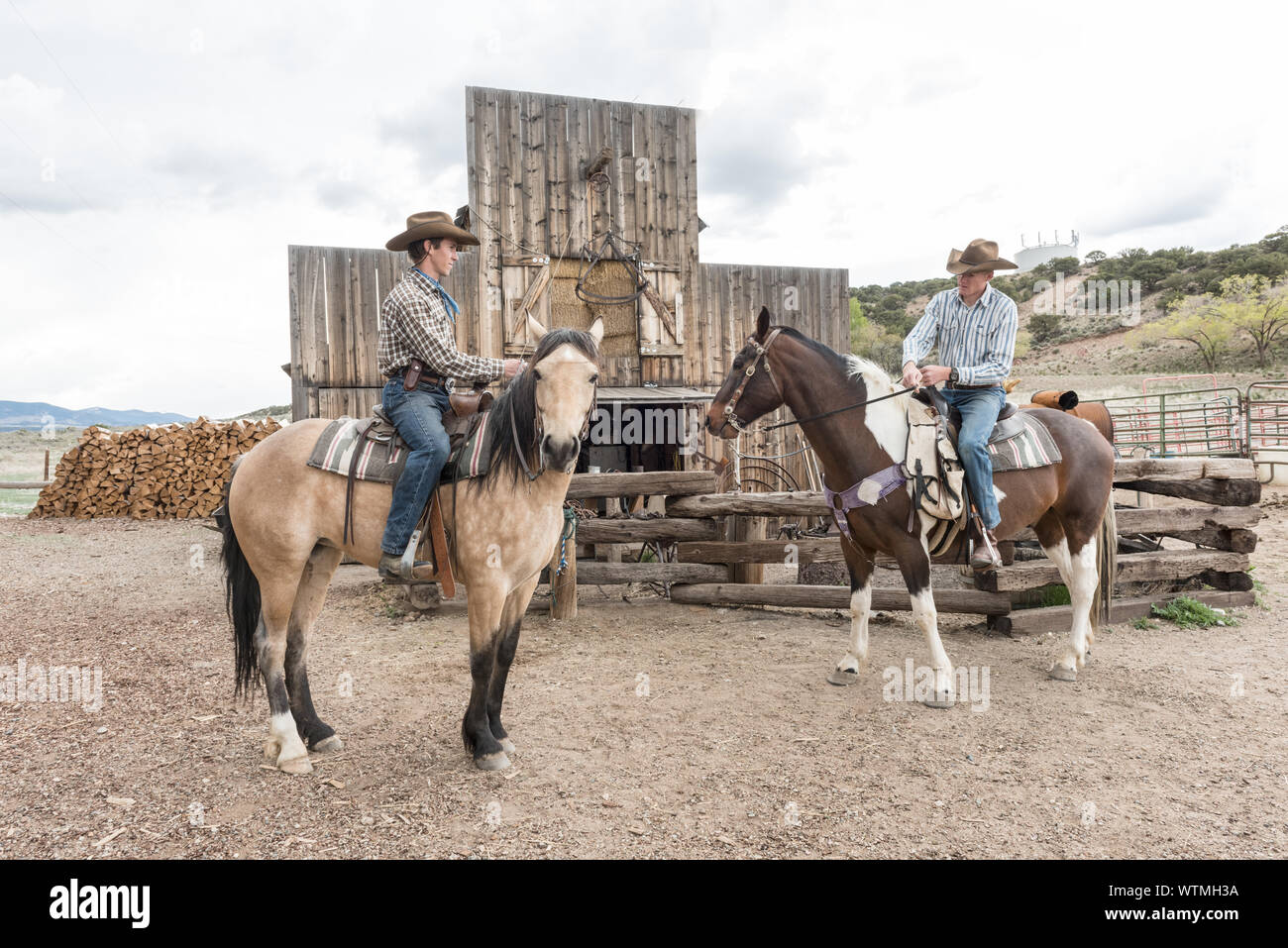 Mounted cowboys Elisha Robertson (left) and Yancey Gullivan converse at ...