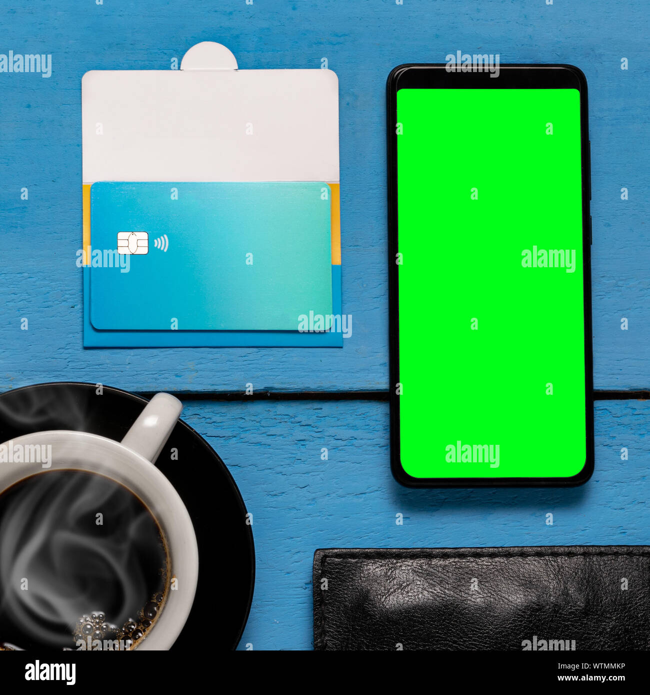 A blue contactless credit card showing chip, with a smartphone, coffee ...