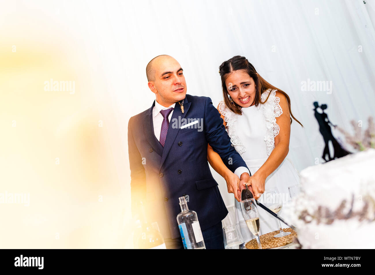 Exited couple of newly weds cutting with a sword the wedding cake Stock ...