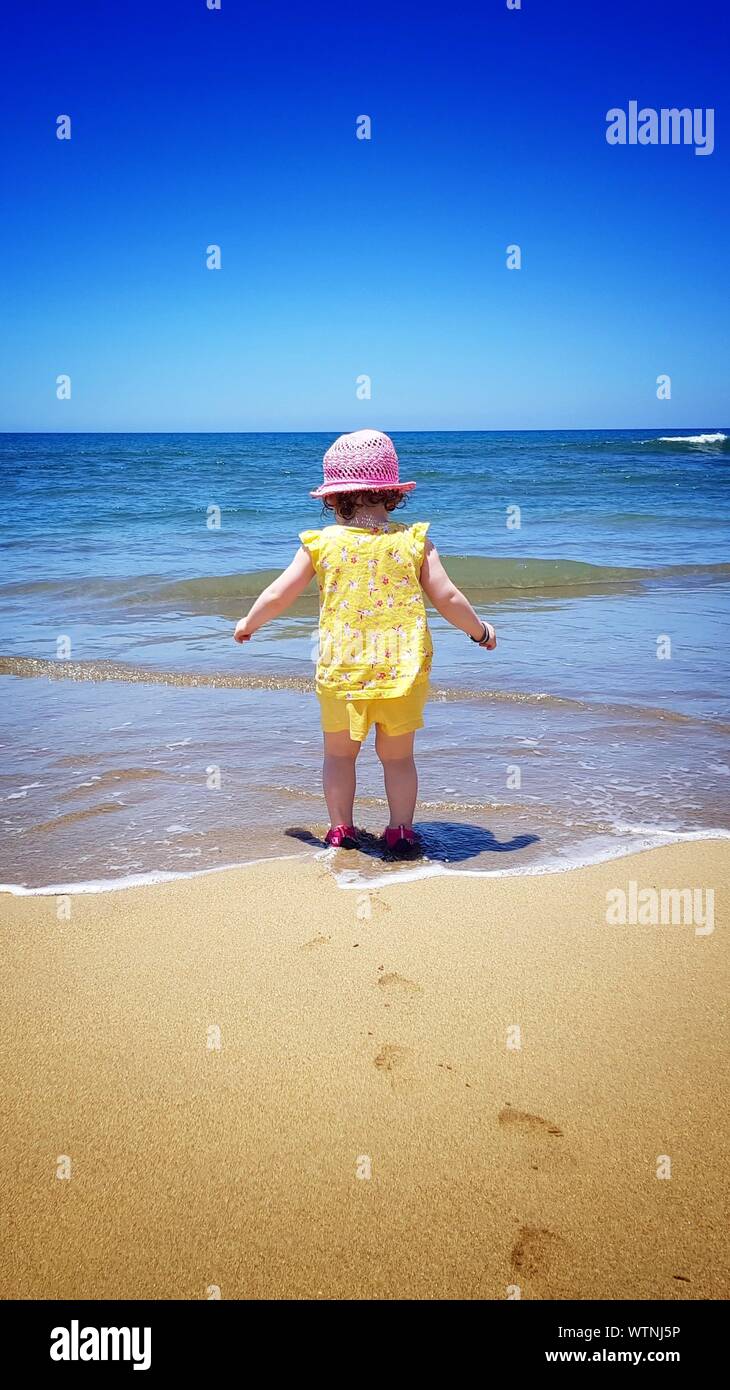 Rear View Of Toddler Girl Standing On Shore At Beach Stock Photo - Alamy