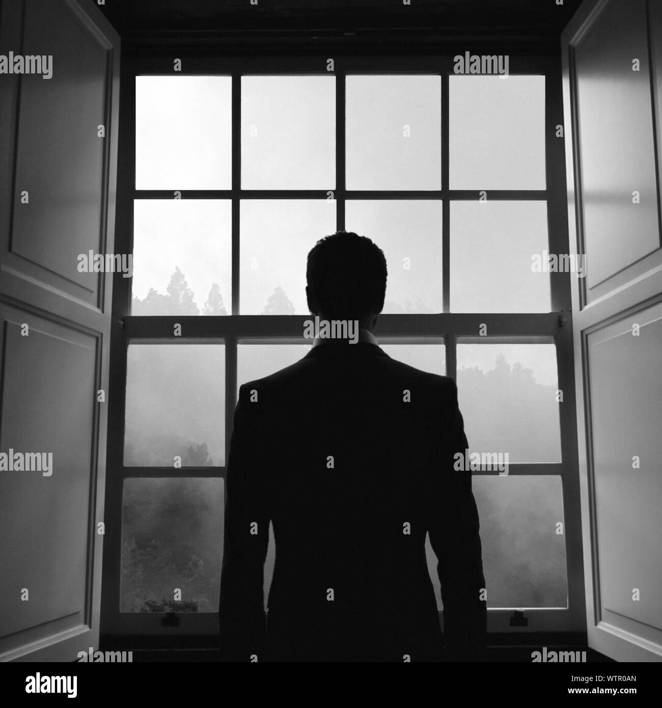 Man looking through window Black and White Stock Photos & Images - Alamy