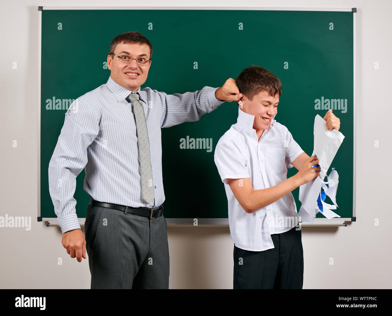 Portrait of a teacher catch the ear funny schoolboy with low discipline ...