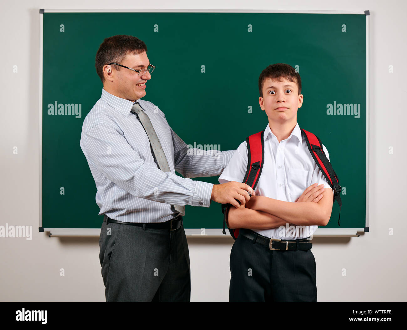 Portrait of a teacher and schoolboy playing at blackboard background ...