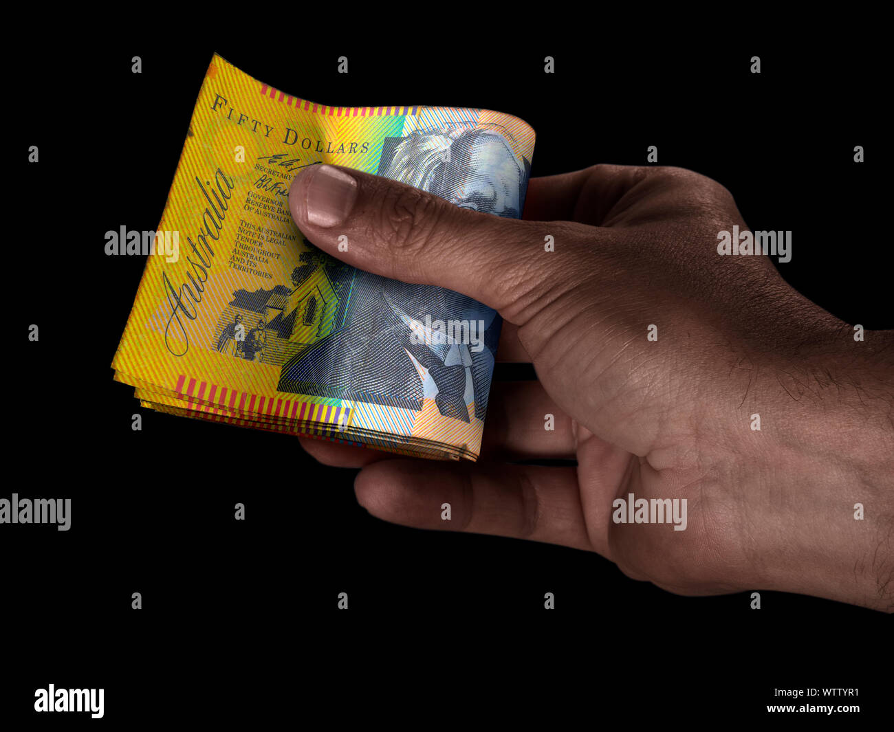 A black male hand handing over a wad of folded australian dollar bank ...