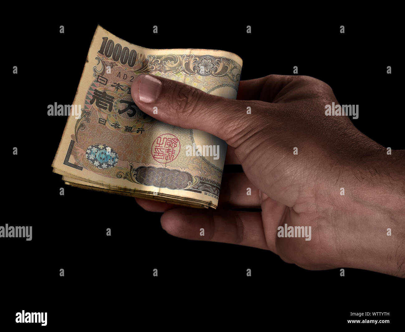 A black male hand handing over a wad of folded Japan Yen bank notes on ...