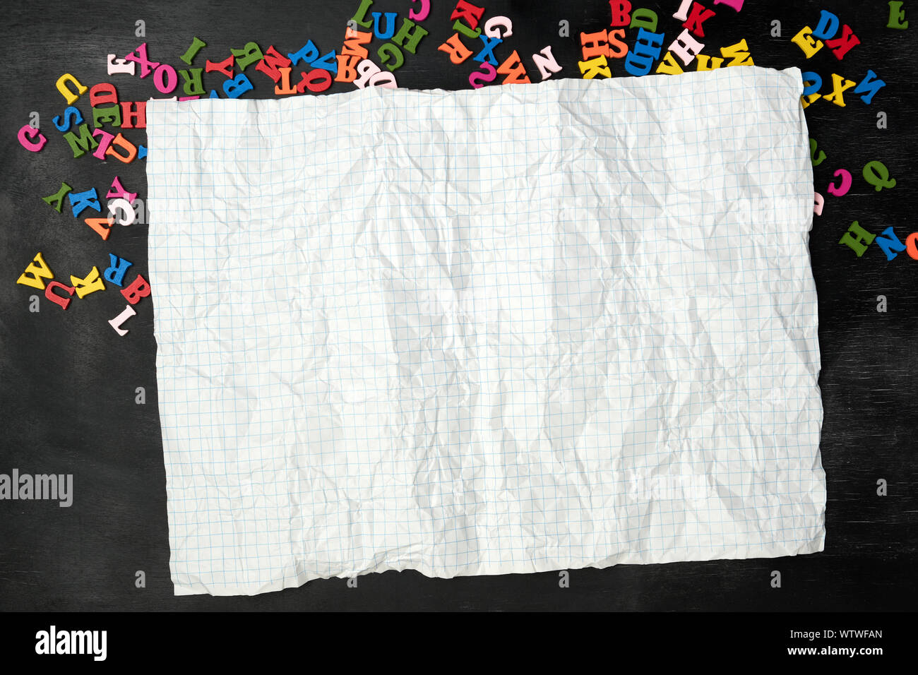 crumpled piece of paper from a school notebook in a cage on a black ...