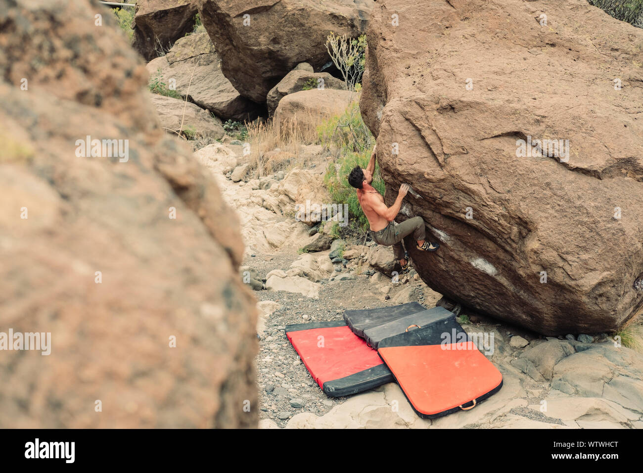 Shirtless man climbing a boulder Stock Photo - Alamy