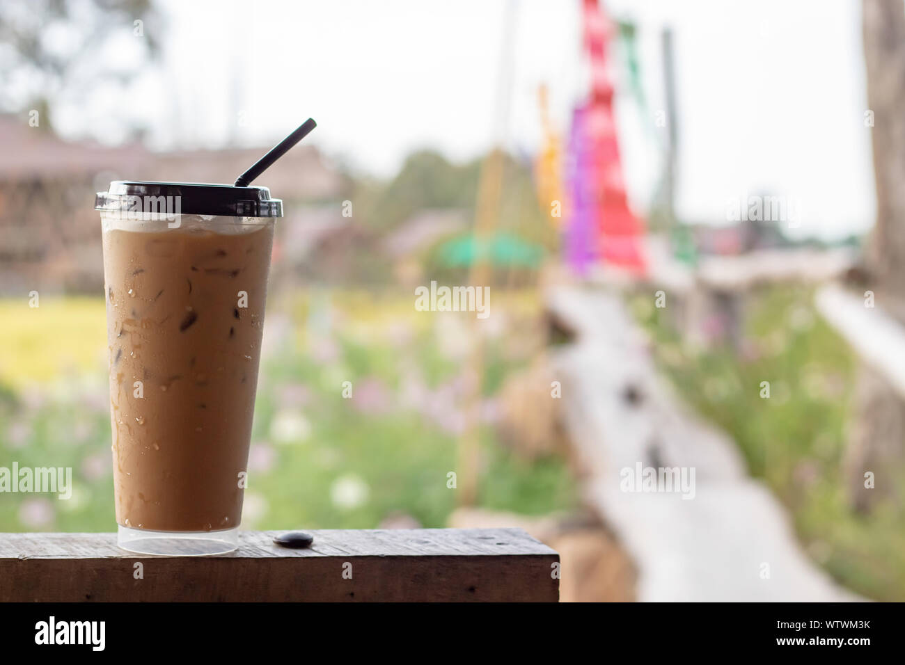 Iced coffee on the wooden floor behind a paddy field and colorful ...
