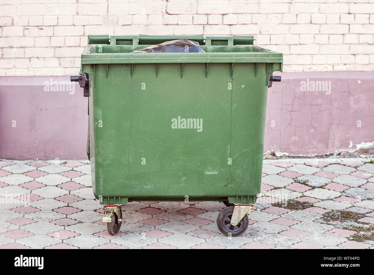 Dumpster on the brick wall background. Garbage bin near building Stock ...